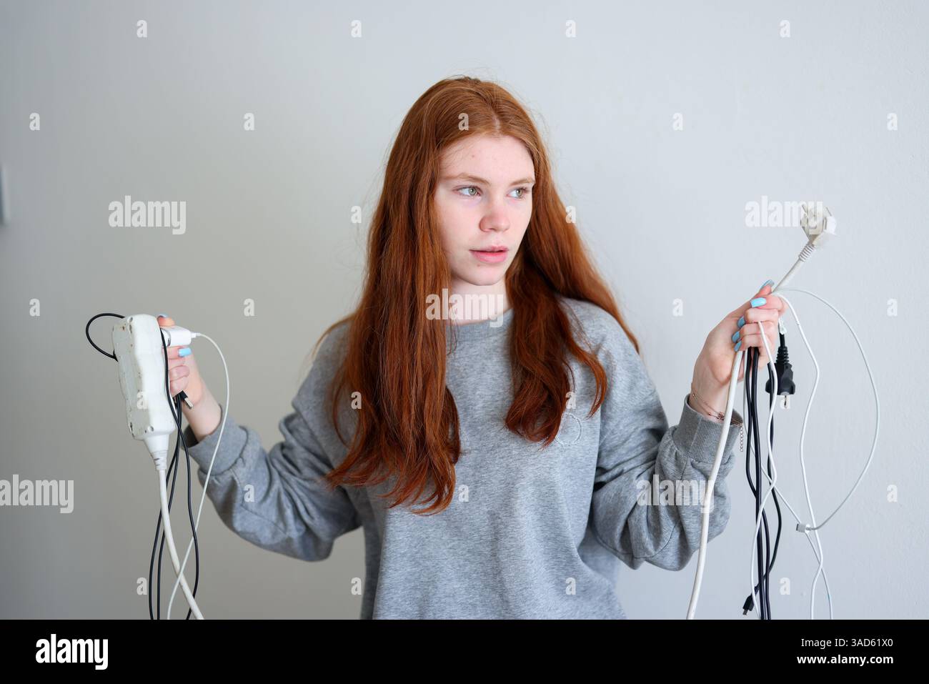 Teenager dealing with electrical plugs and extension cords, tech ...