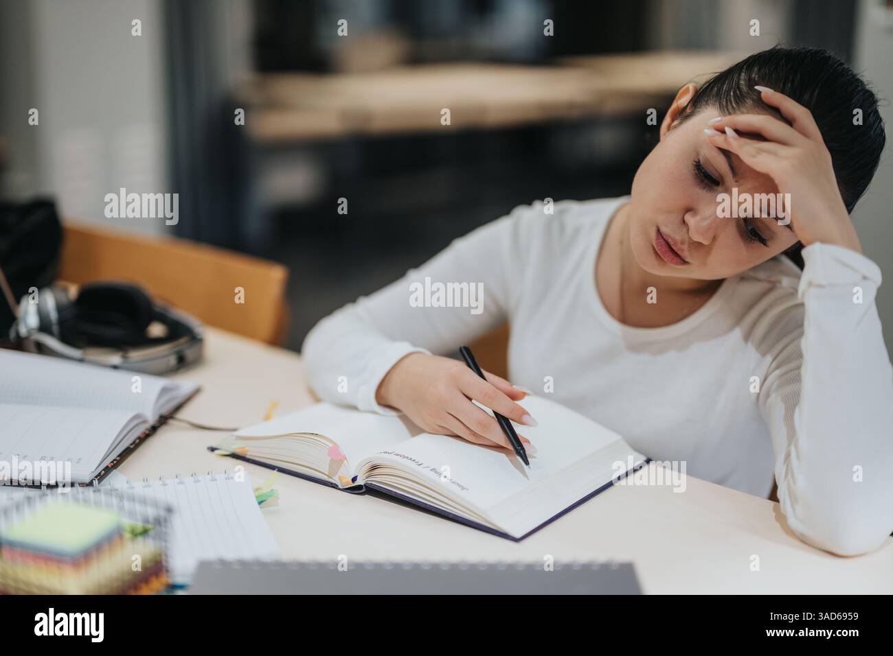 Young student studying intensely at a desk with books and notes Stock ...