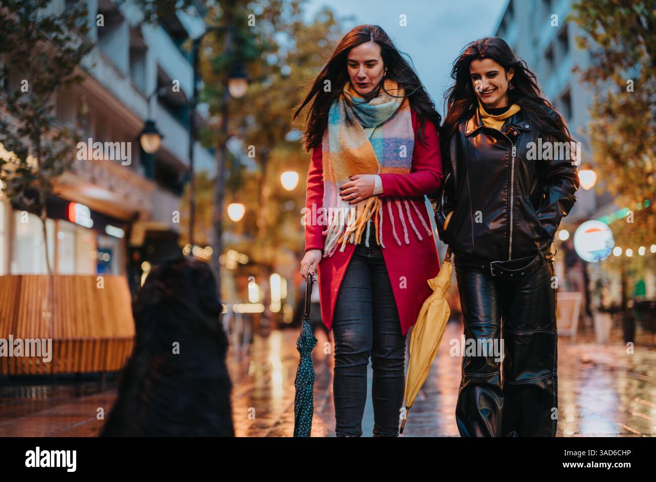Two women walking together through illuminated city streets during the ...