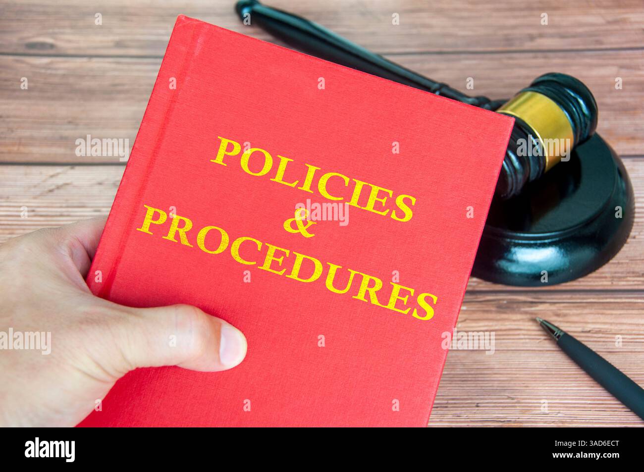 Hand holding Policies and Procedures book with gavel on a wooden table ...
