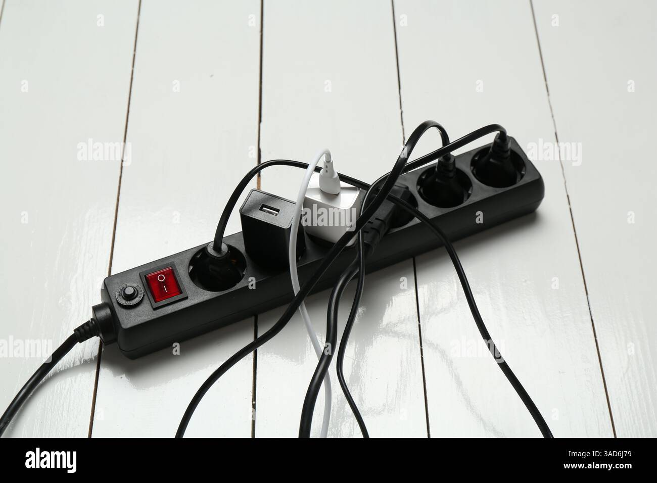 Extension power board overloaded with plugs on white wooden floor Stock ...