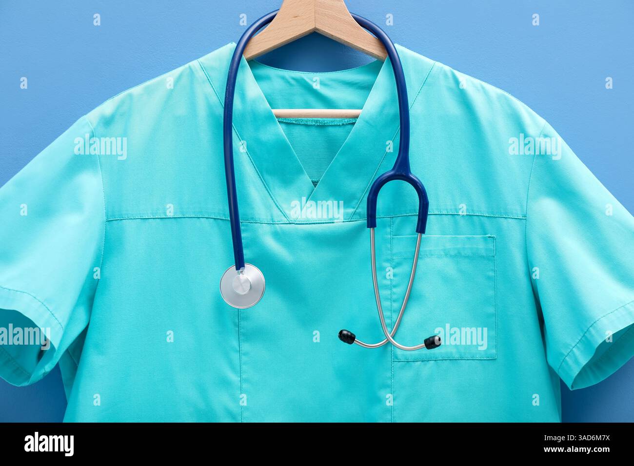 Medical worker uniform with stethoscope on hanger against blue ...