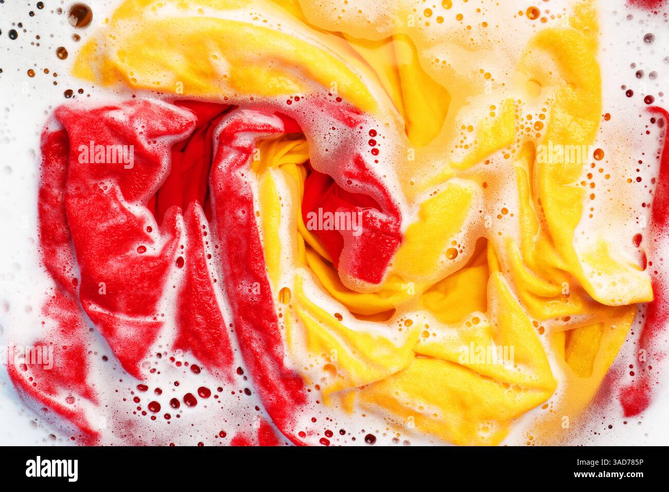 Colorful clothes soaked in water before washing, top view Stock Photo ...