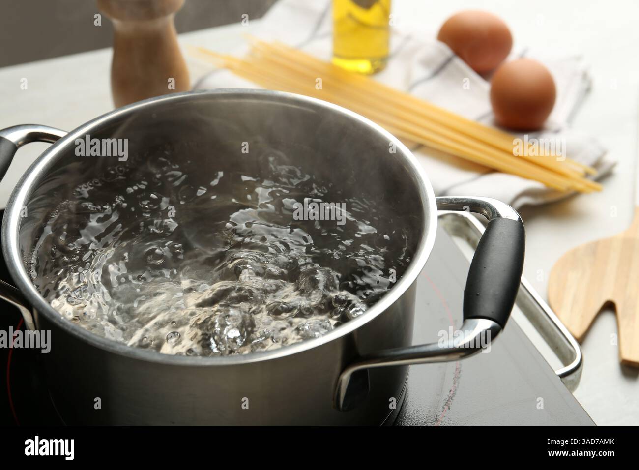 Cooking pot with boiling water and stove on white table, closeup Stock ...