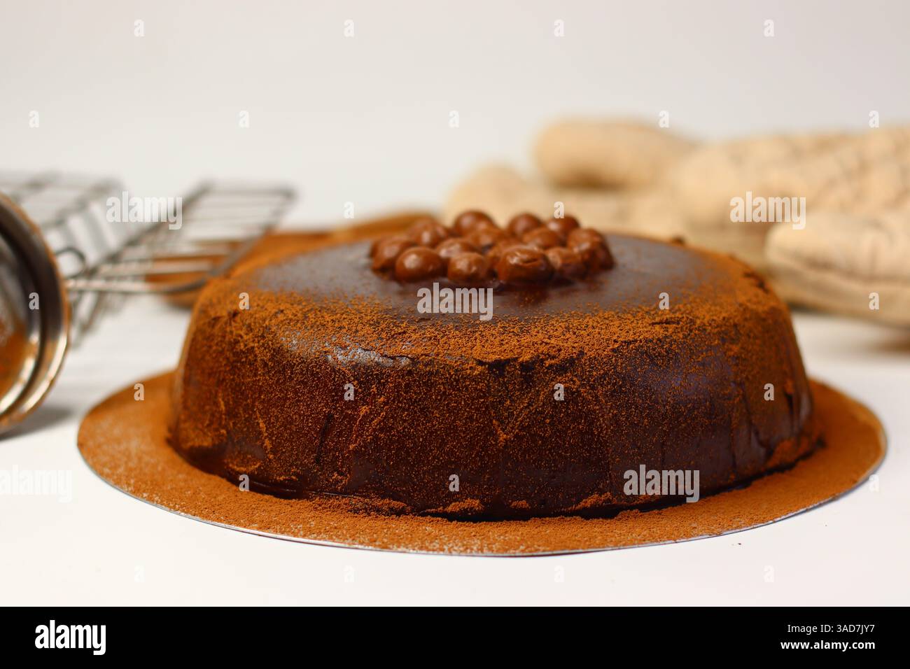 Rich chocolate cake topped with crunchy chocolate coated nuts, dusted ...