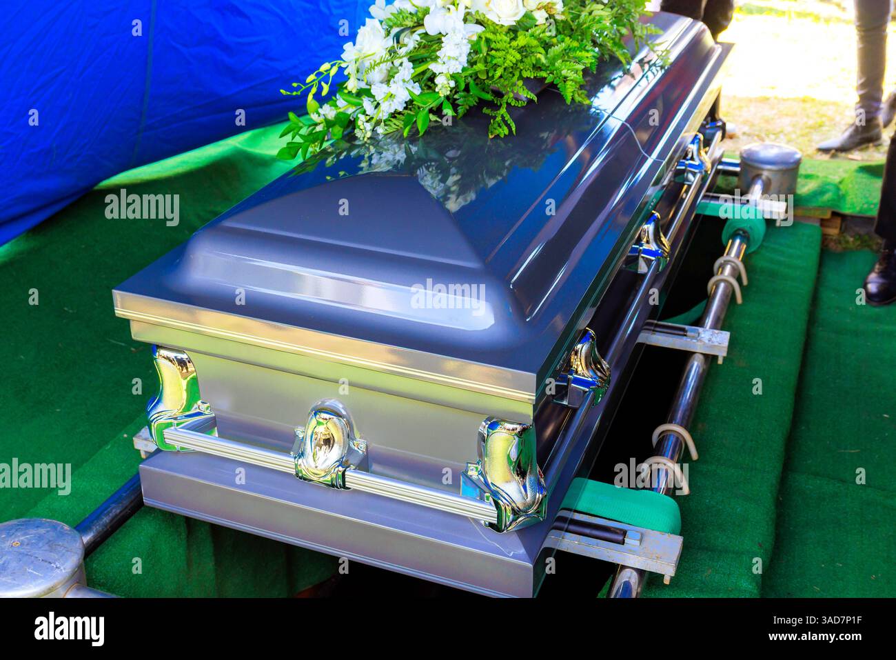 Funeral silver casket as decorated coffin is lowered at during burial ceremony Stock Photo - Alamy