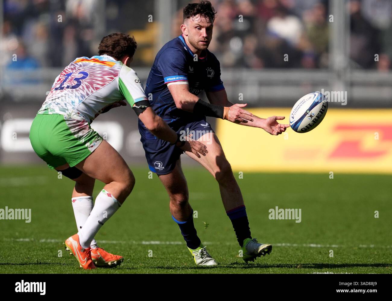Leinster's Hugo Keenan (right) passes the ball before being tackled by ...