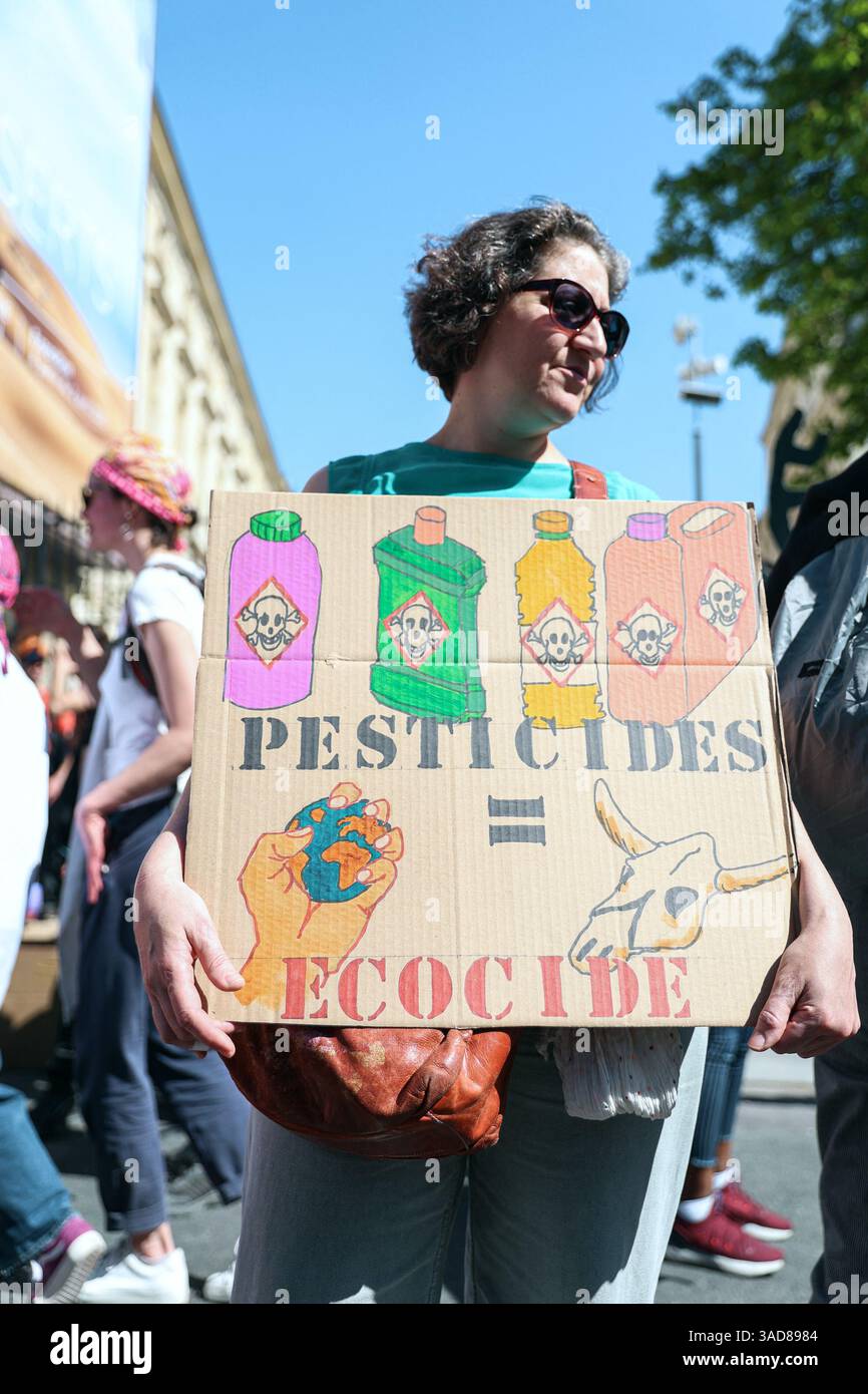 A protester holding a sign with the words "pesticides equal ecocide ...