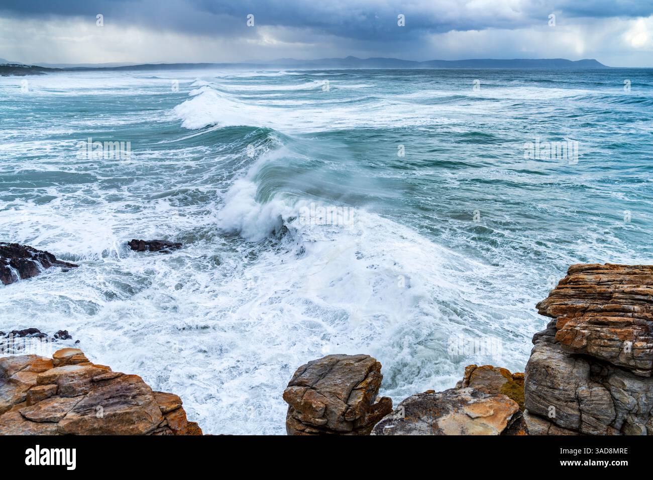 Huge waves crashing onto a rocky shoreline under a brooding sky ...