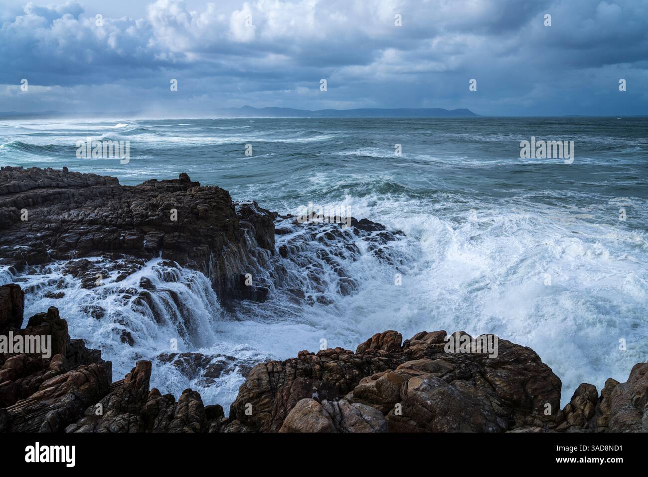 Huge waves crashing onto a rocky shoreline under a brooding sky ...