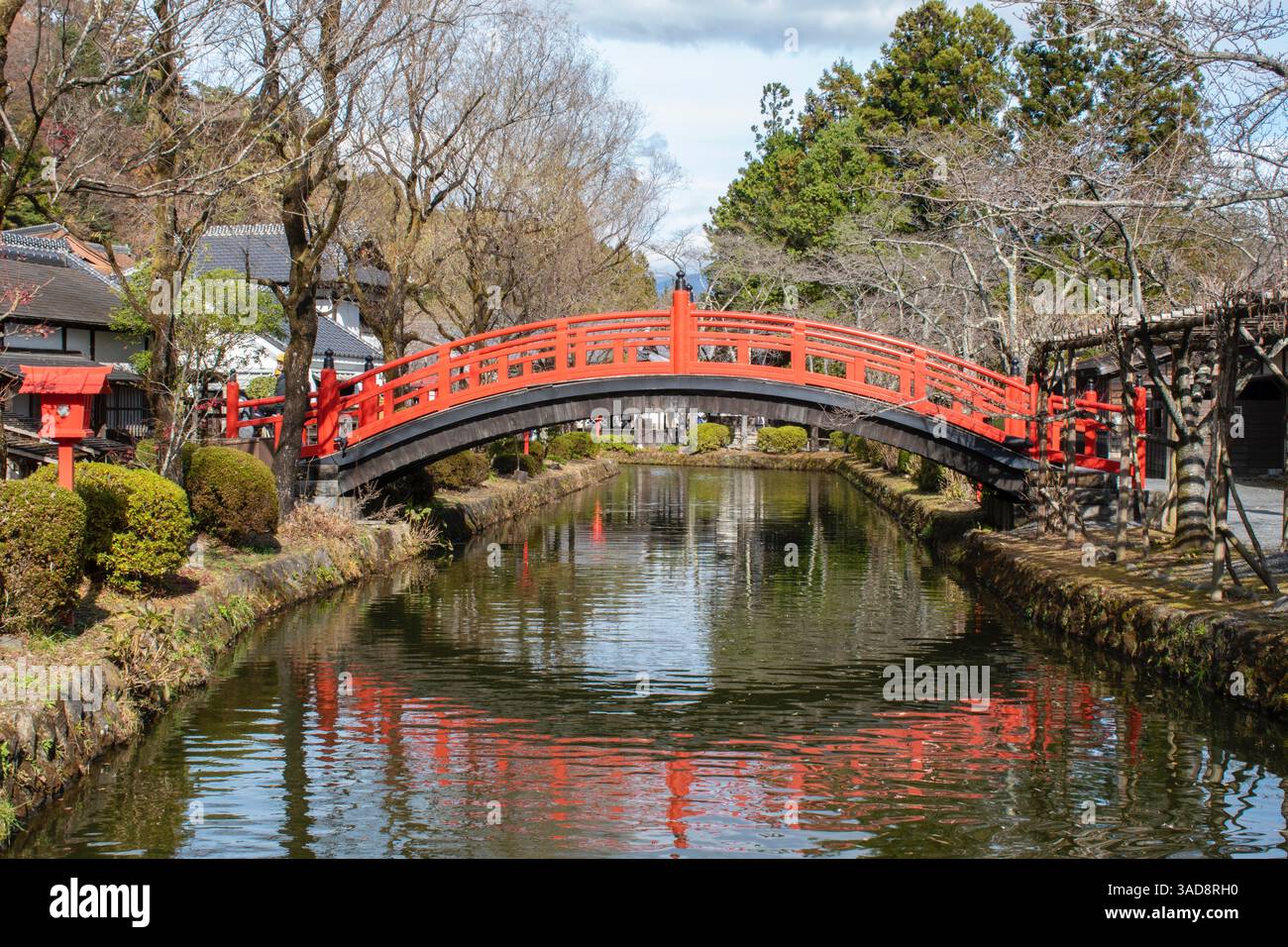 A traditional red and black wooden bridge surrounded by trees and red ...