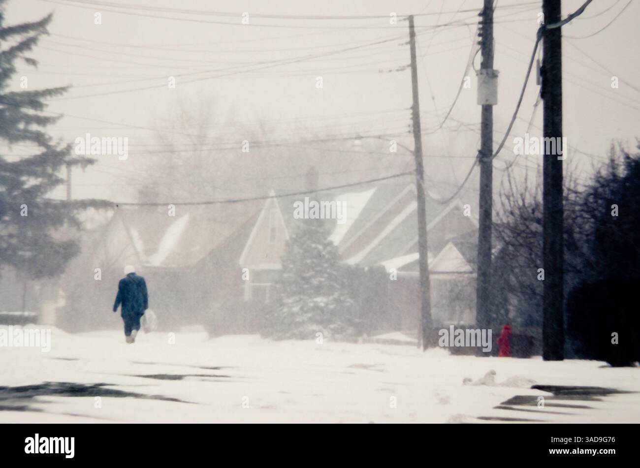One person walking into the distance on an urban street in a snowstorm ...