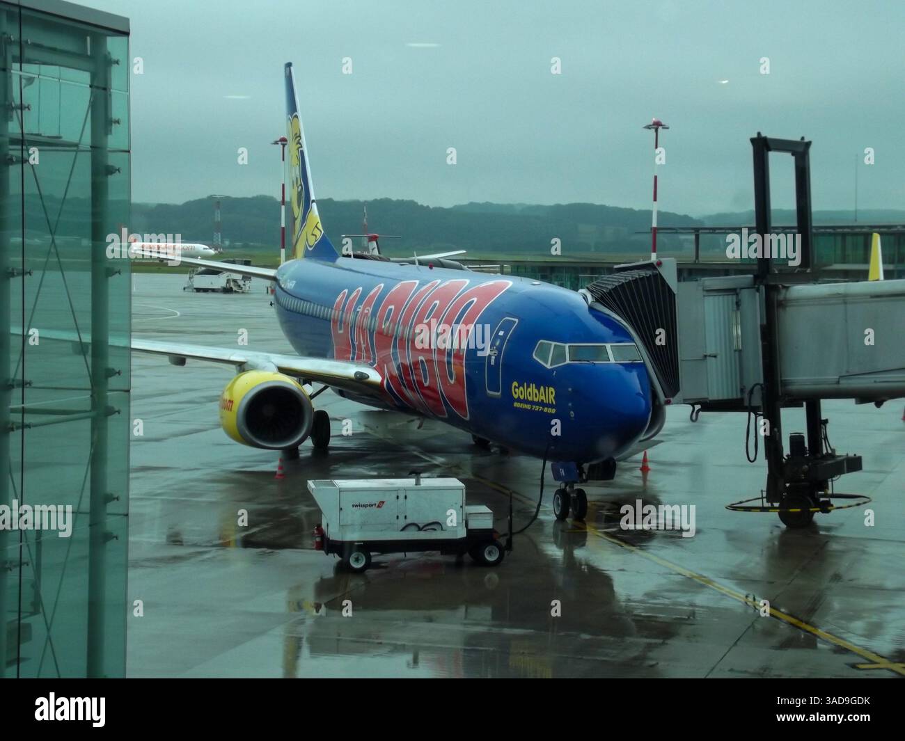 A colorful airplane with a blue and yellow design parked at an airport ...
