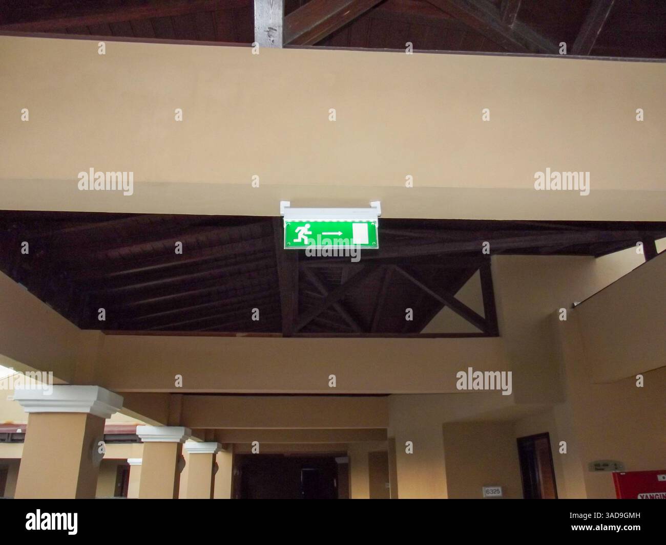 A green emergency exit sign mounted on a ceiling, indicating the ...