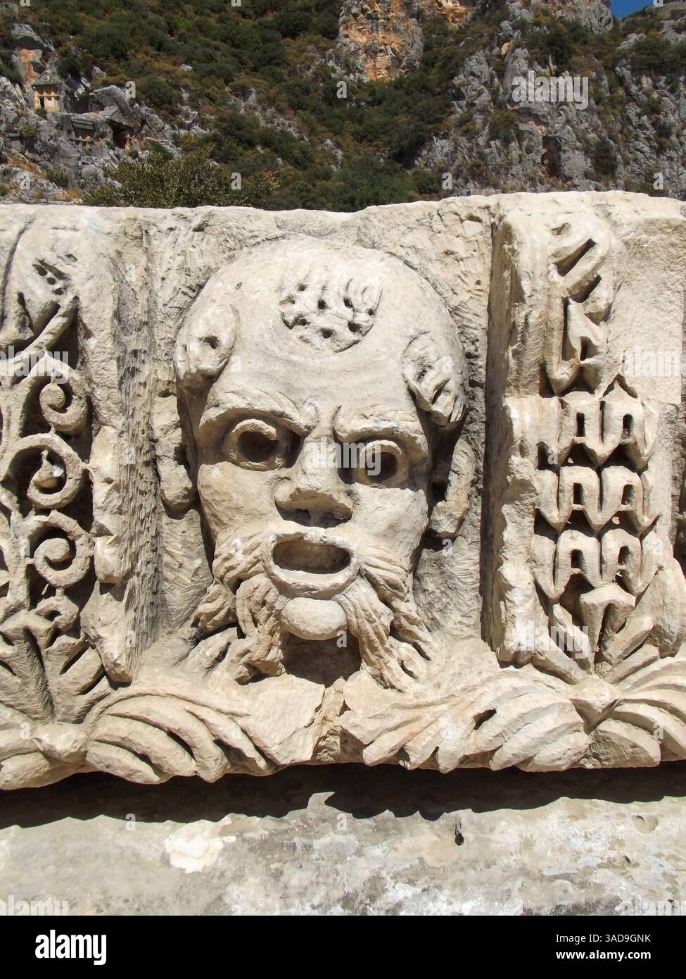 An ancient stone relief depicting a fierce face with a beard ...