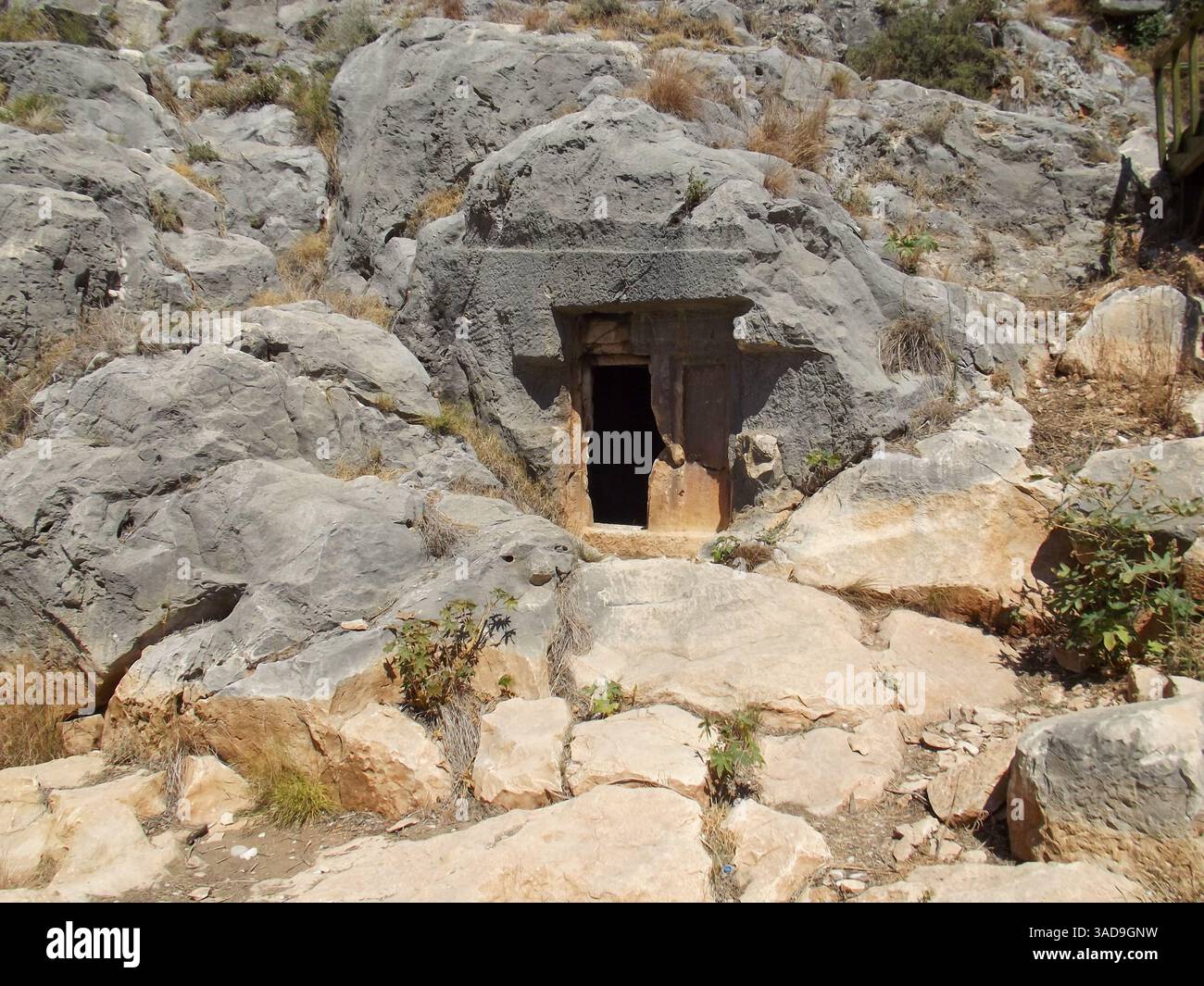 An ancient rock-cut tomb entrance nestled among rocky terrain ...