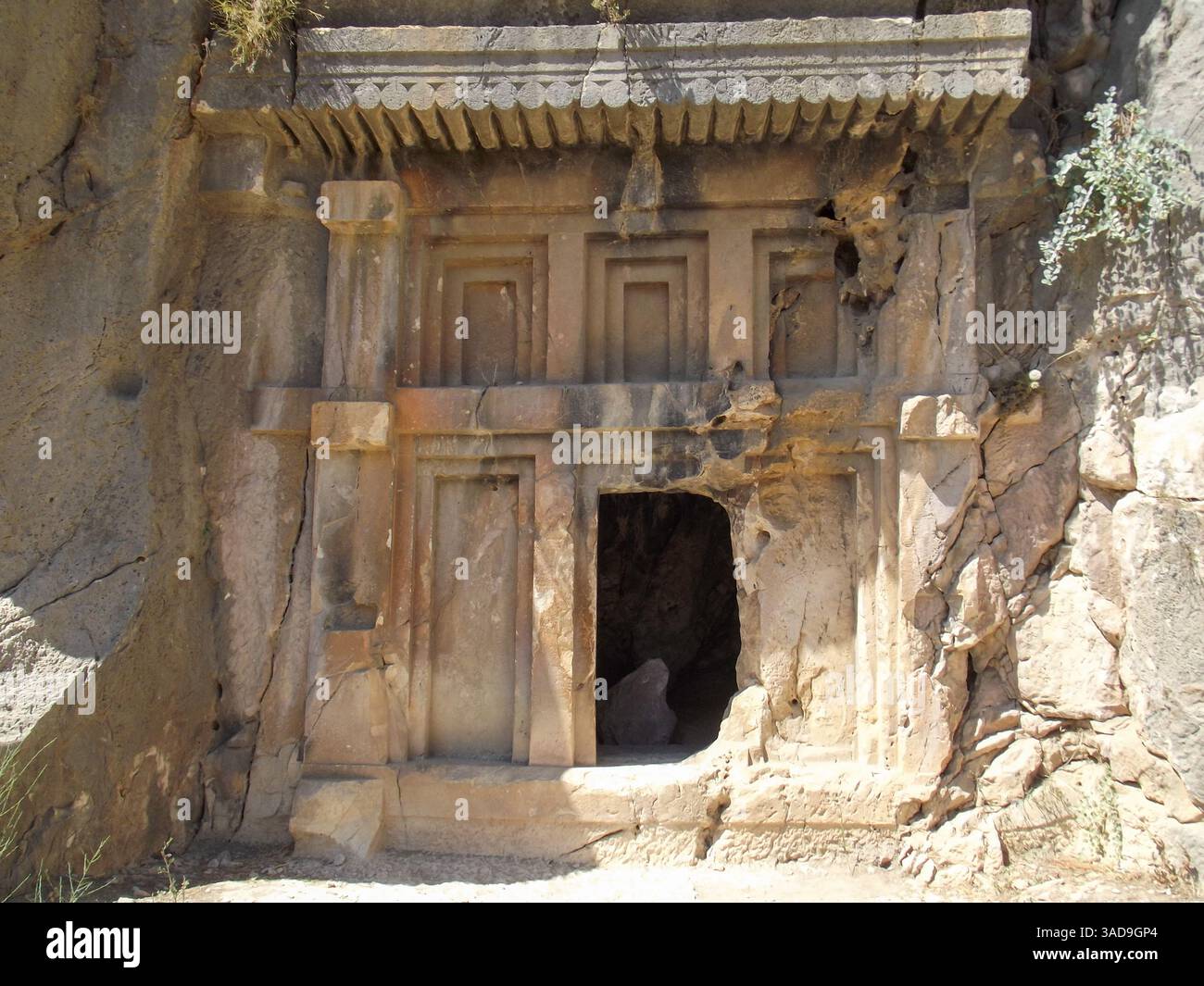 An ancient rock-cut tomb entrance with intricate carvings, surrounded ...