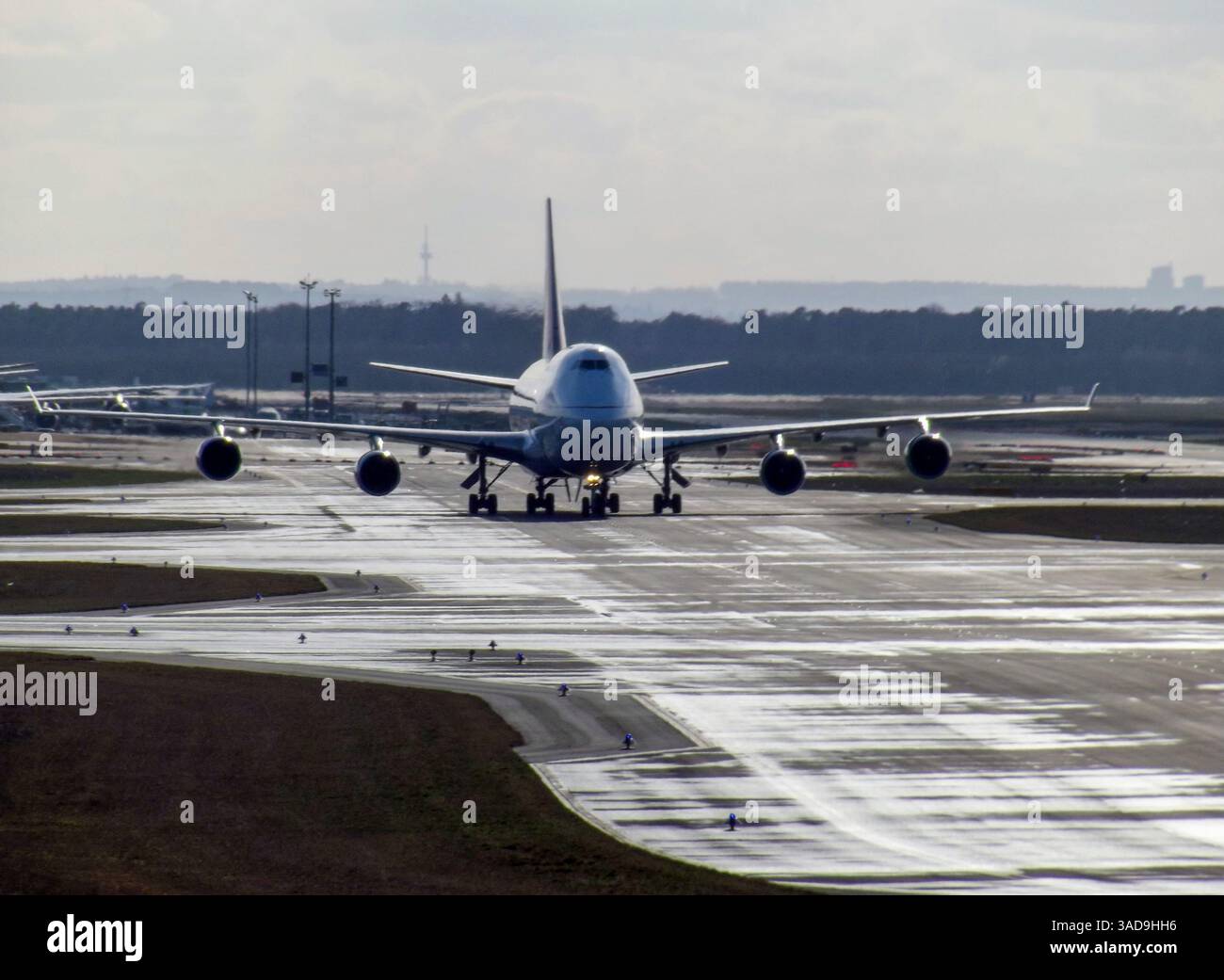 A large passenger airplane, likely a Boeing 747, is taxiing on a wet ...