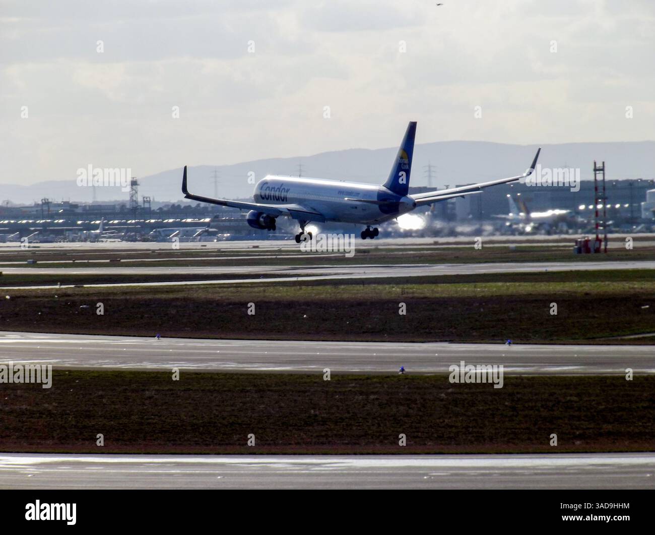 A commercial airplane landing on a runway with a cloudy sky in the ...