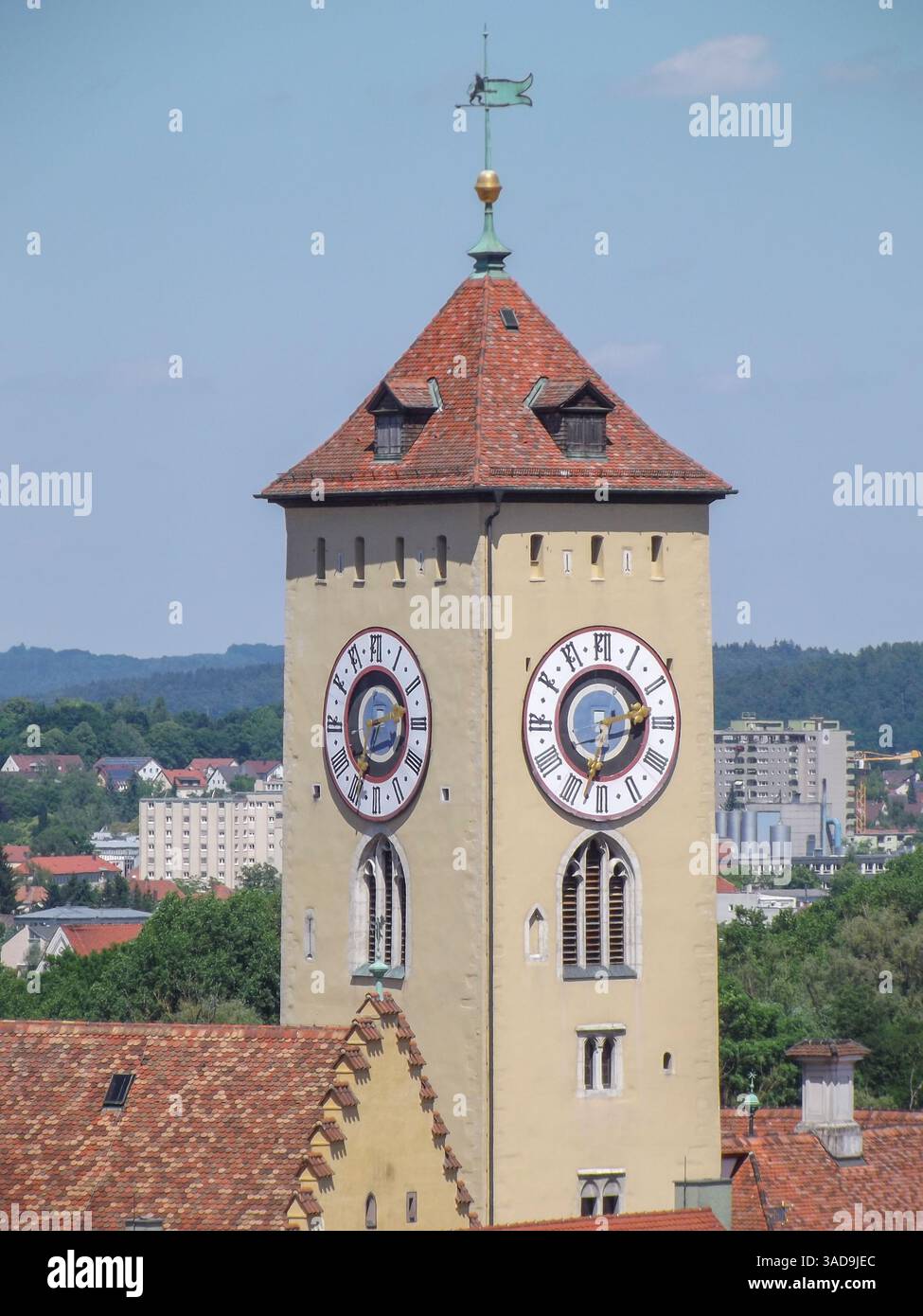 A tall clock tower with a red-tiled roof and two large clock faces. The ...