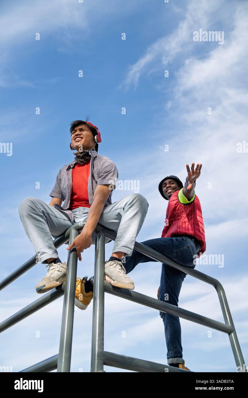 two young man poses on a metal railing Stock Photo - Alamy