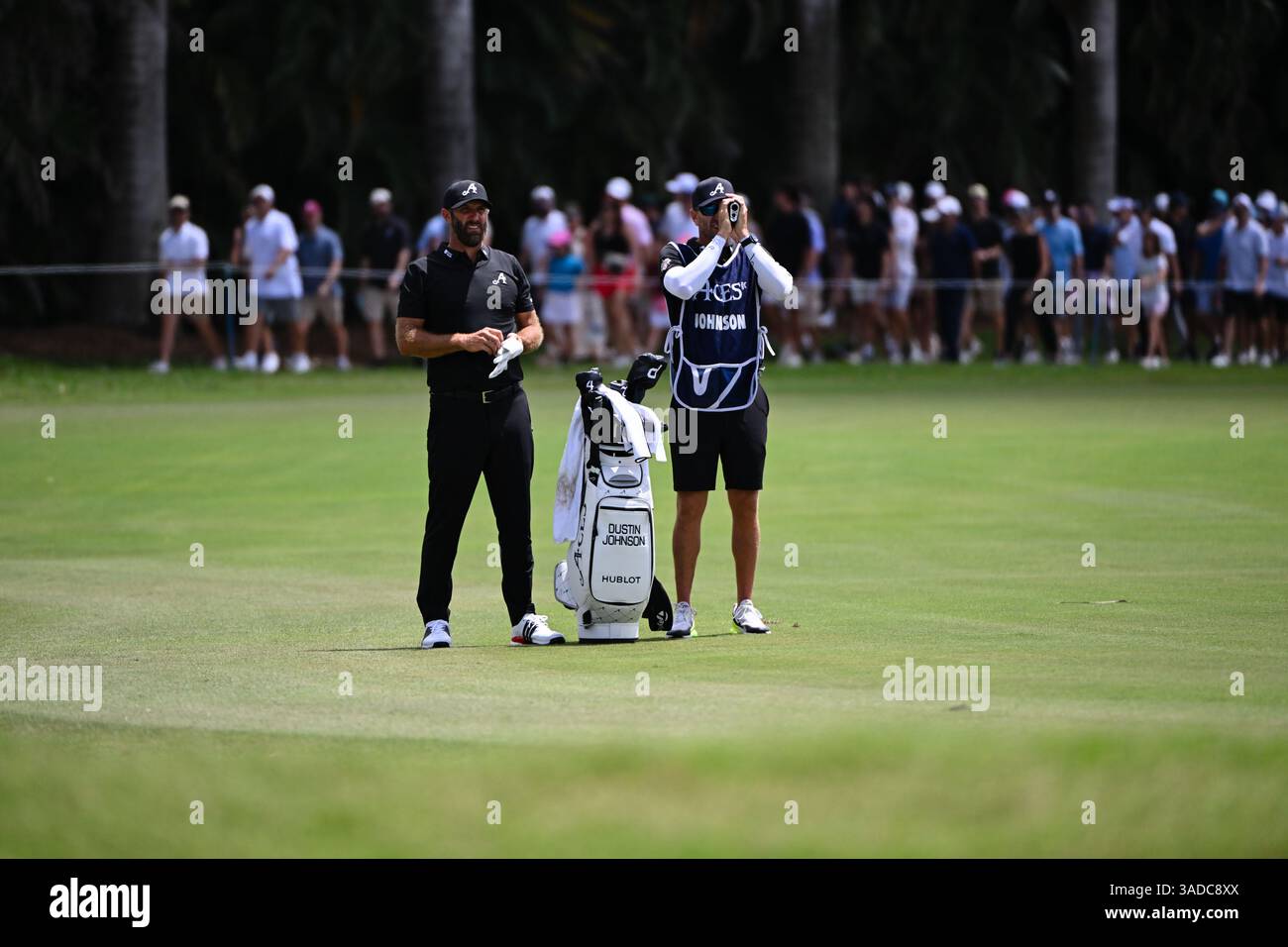 Dustin Johnson, Captain of the 4Aces GC looks on as his caddie checks ...