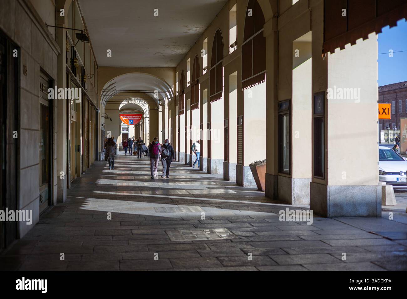 Turin, Italy - Nov 08 2021: Pedestrians walk under the arched porticoes ...
