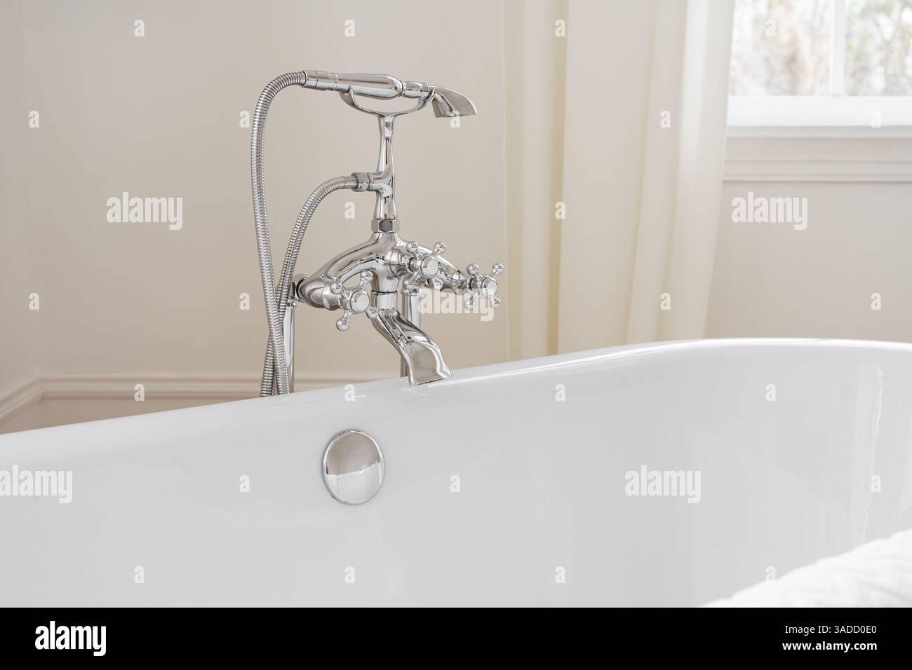 Shiny metal chrome faucet on white freestanding bathtub. Plumbing ...