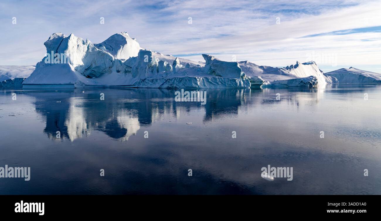 A stunning view of a large iceberg floating in calm waters, reflecting ...