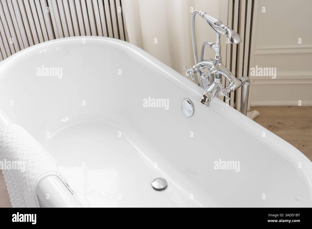 Shiny metal chrome faucet on white freestanding bathtub. Plumbing ...