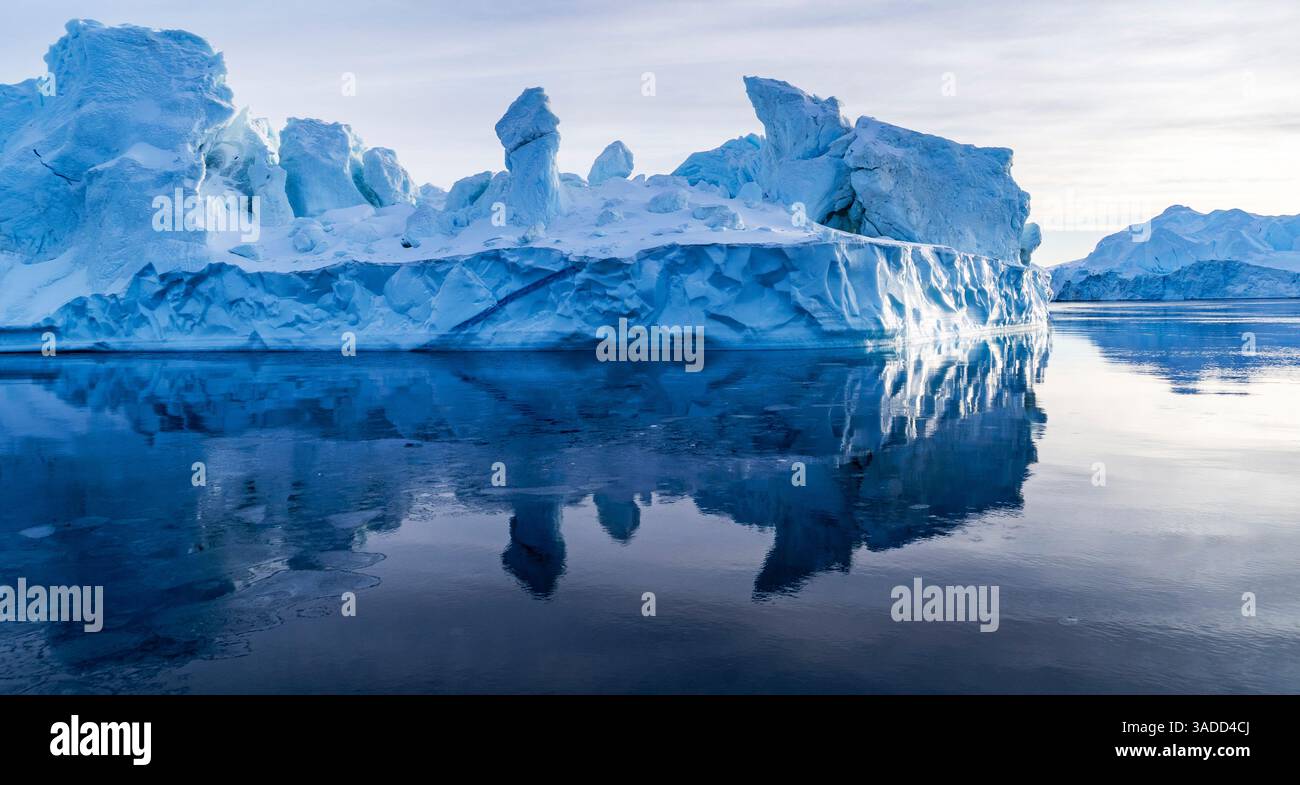 A stunning view of an iceberg floating in calm waters, reflecting its ...