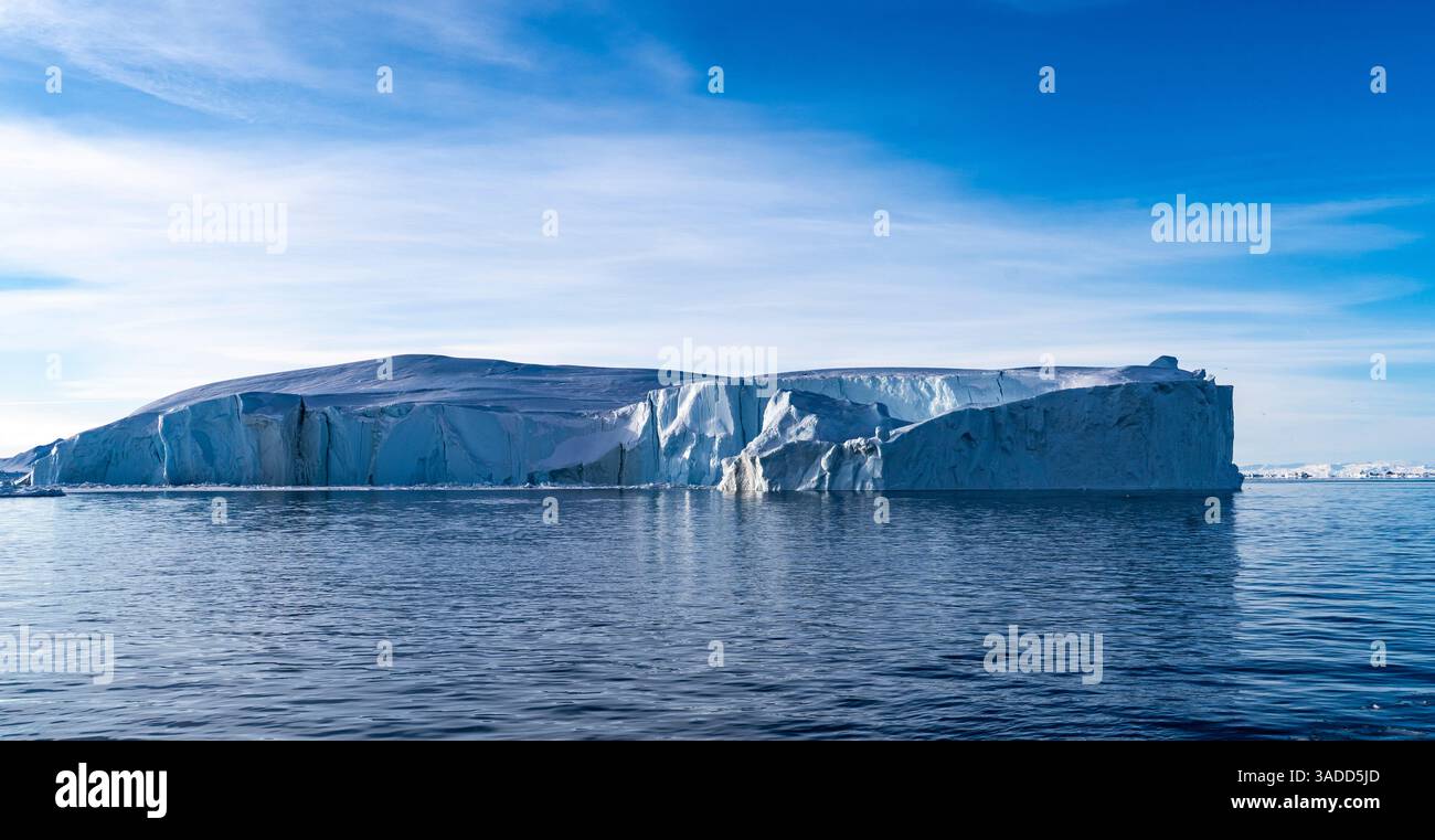 A stunning view of a large iceberg floating in calm waters under a ...