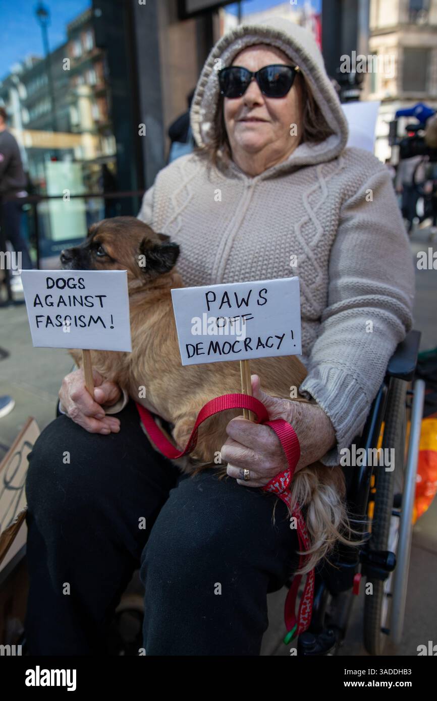 London, Westminster, UK. 19th Mar, 2025. An activist holds two placards ...