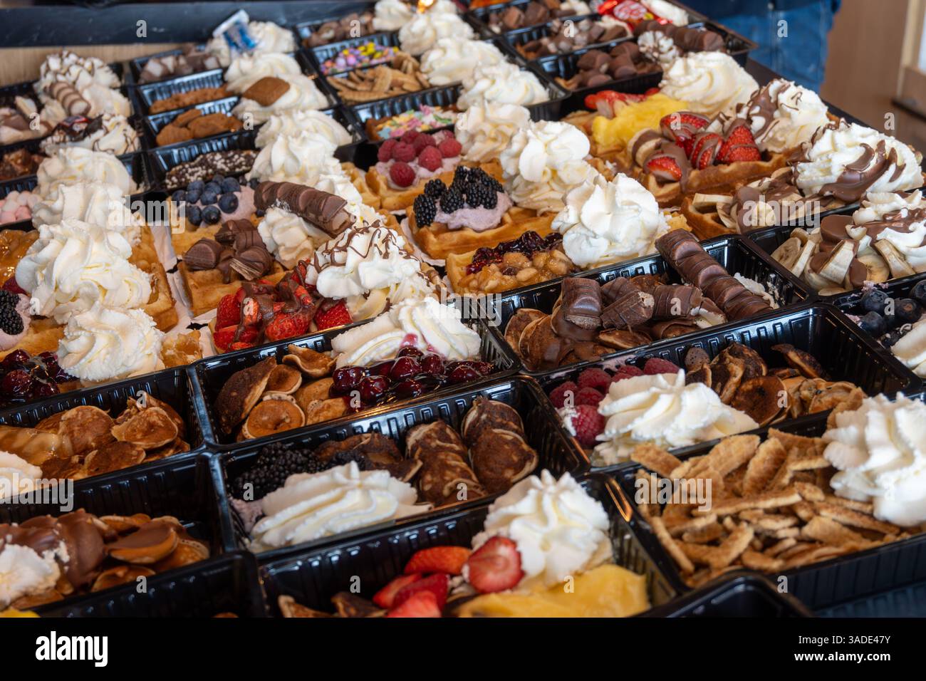 Variety of fresh baked waffles richly decorated with different toppings ...