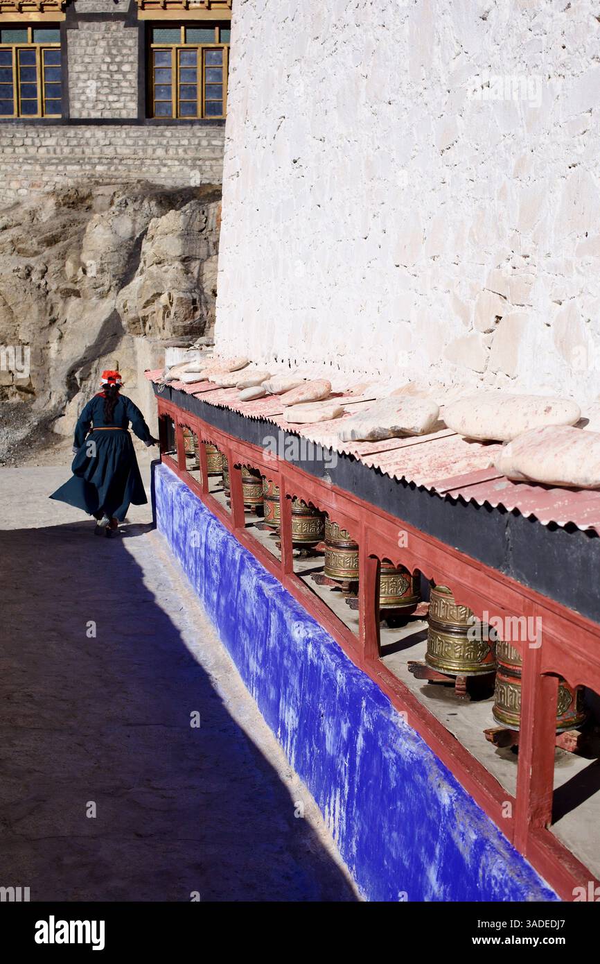 A Buddhist monk walks past prayer wheels at Shey Palace monastery in ...