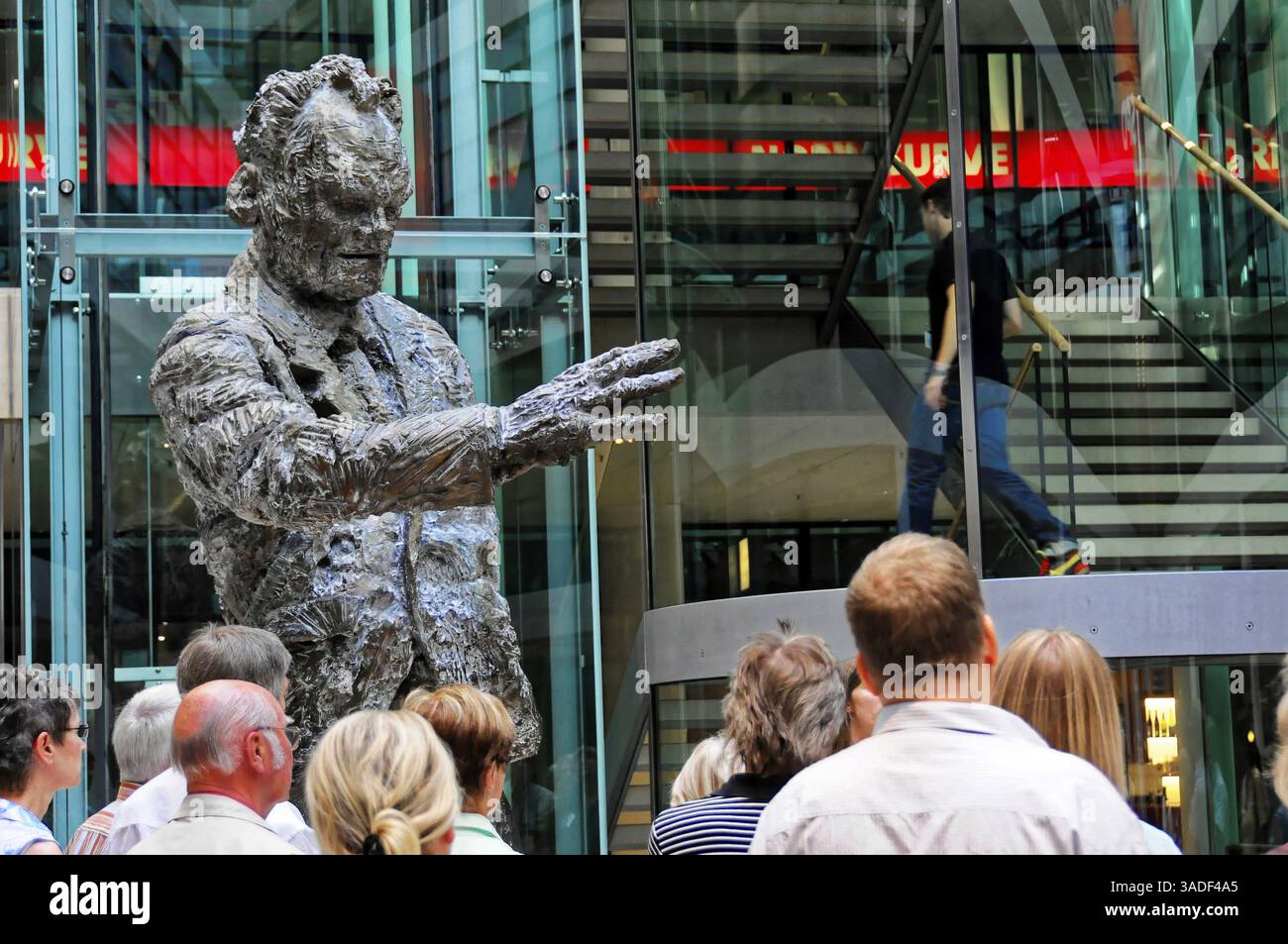 A bronze sculpture of a man stands in a modern building at an ...