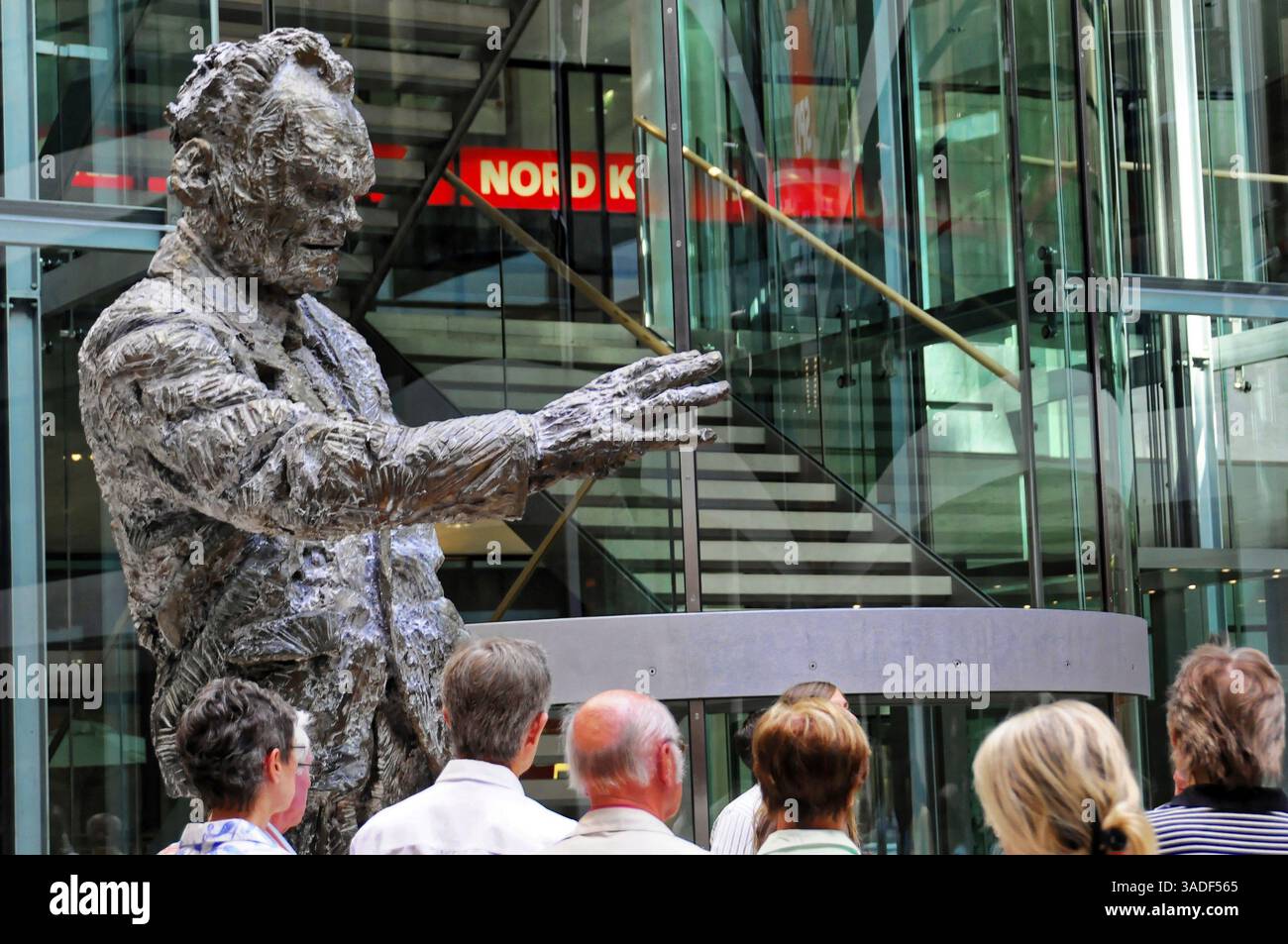A bronze sculpture of a man stands in a modern building at an ...