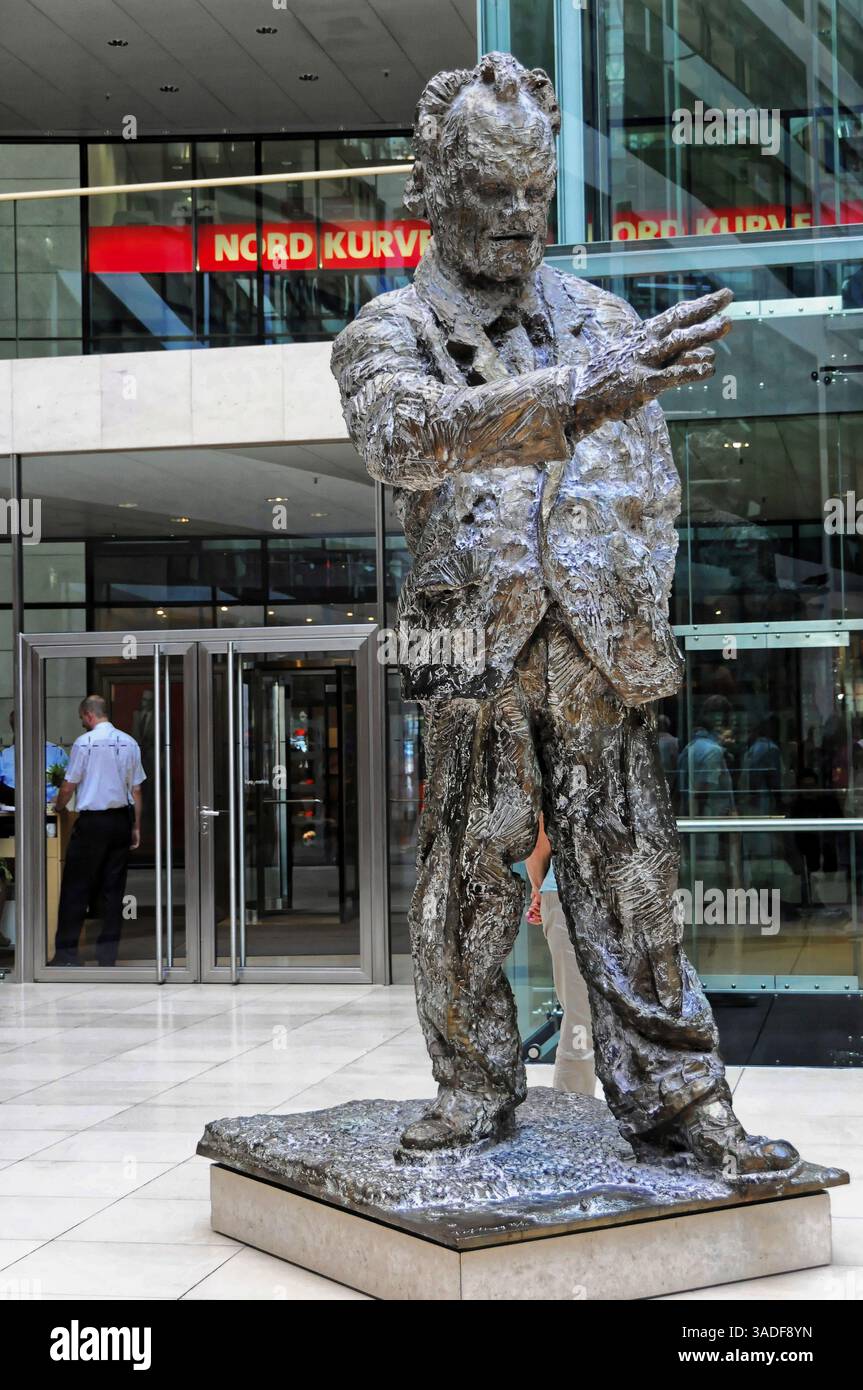 A bronze sculpture of a man stands in a modern building at an ...