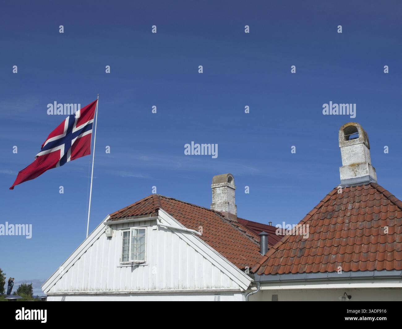 Traditional house with Norwegian flag in front of clear blue sky ...