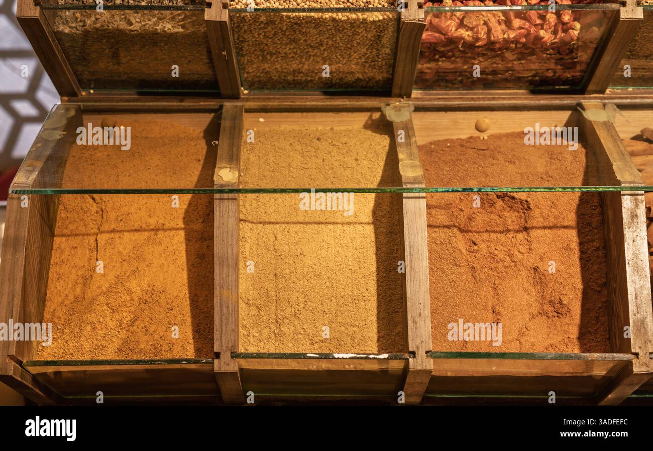Wooden display of various spices in a market, with glass partitions and ...