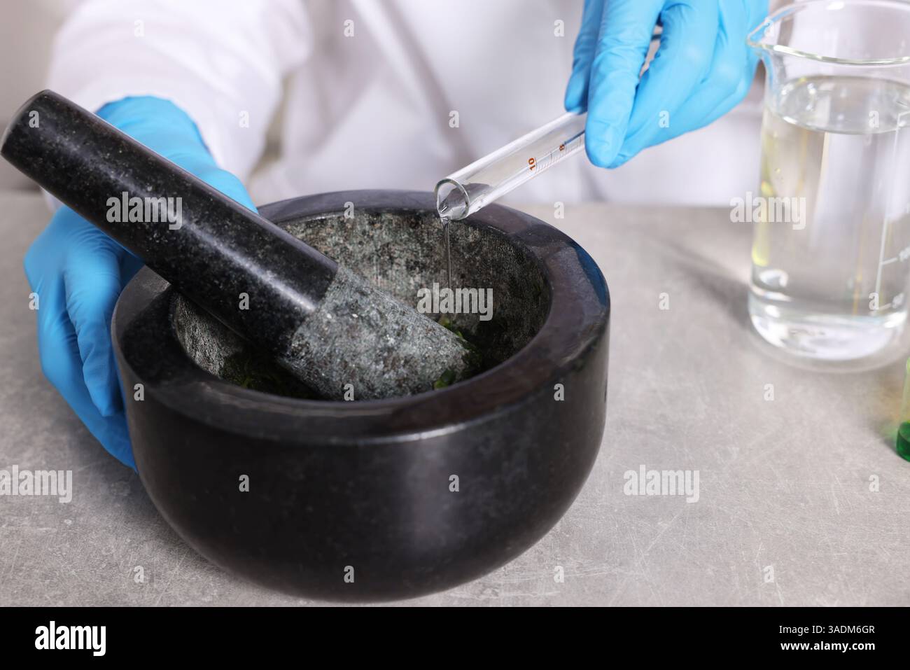 Biochemistry. Scientist with mortar and pestle working at grey table ...