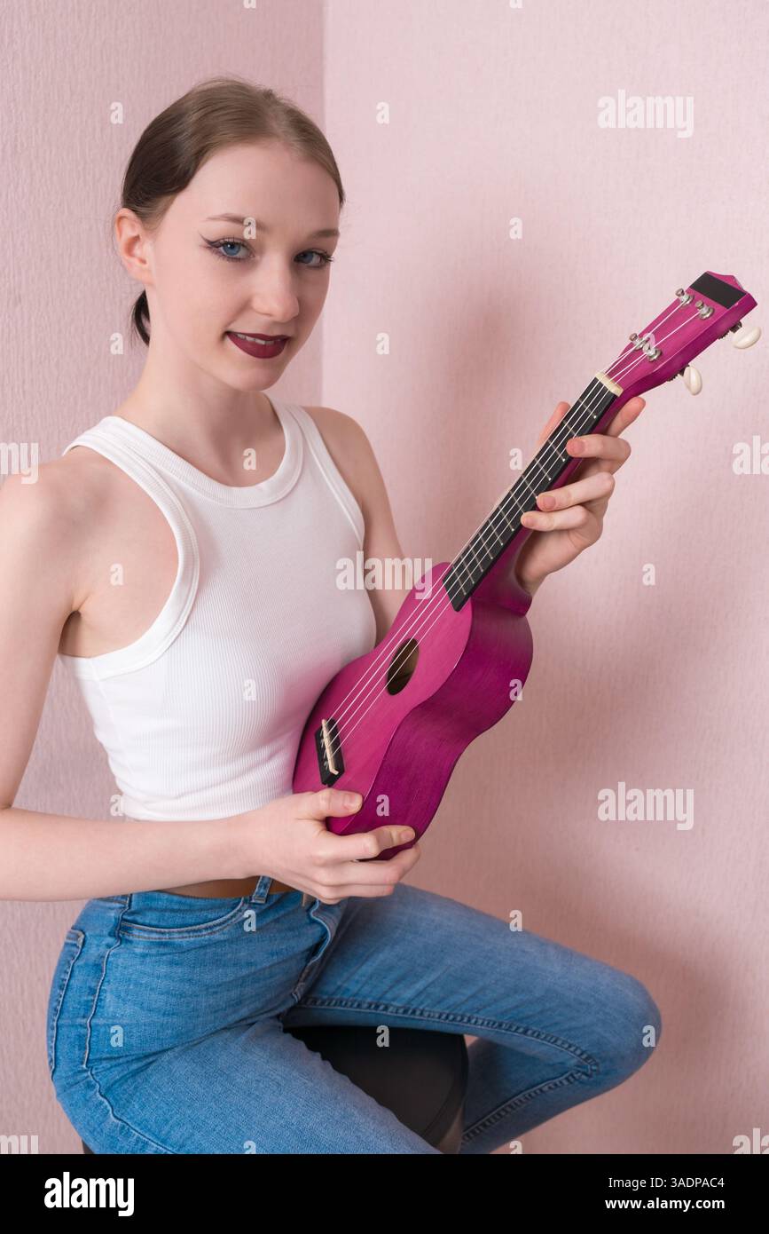 Young woman musician in positive light, holding ukulele. Her face ...