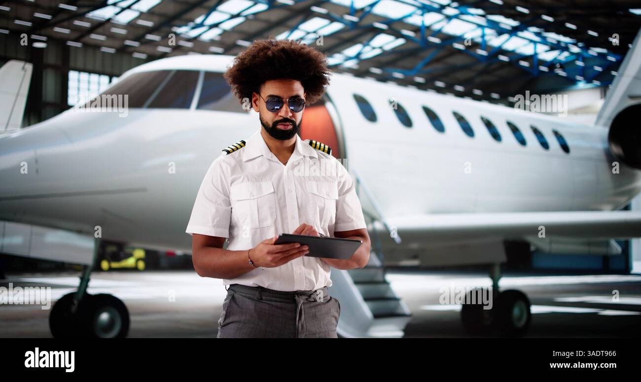 Professional African-American pilot smiling while using tablet for ...