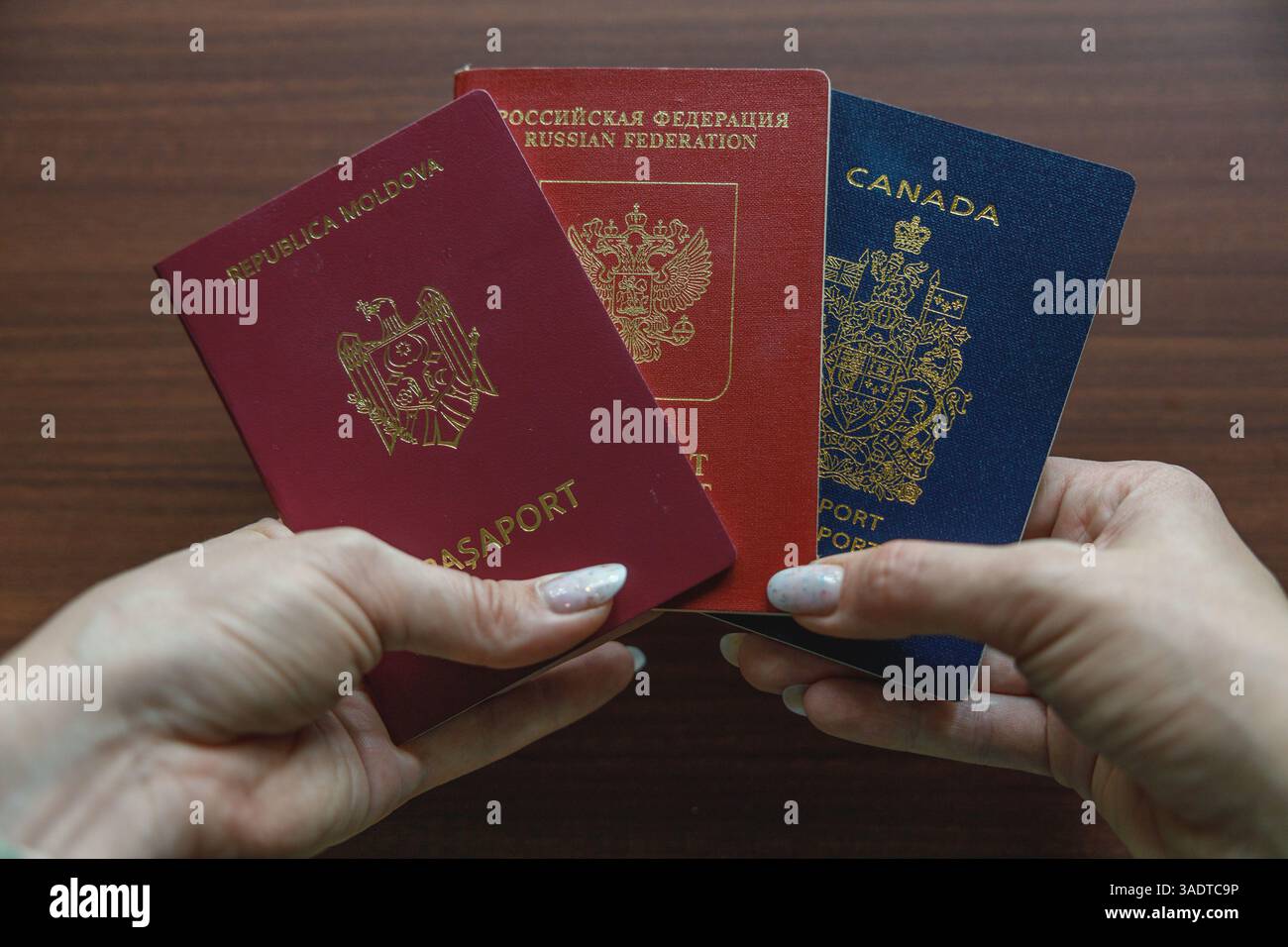 Vancouver, Canada - March 18,2025: Hands holding three passports fanned ...