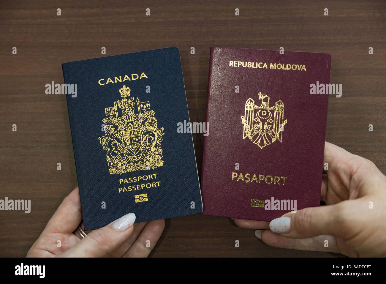 Vancouver, Canada - March 18,2025: Hands holding two passports side by ...