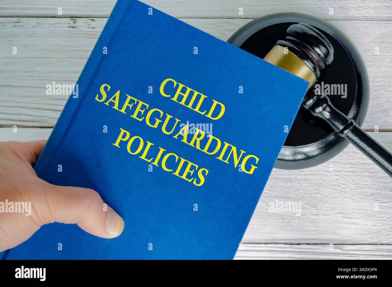 Hand holding Child Safeguarding Policies book with gavel background ...