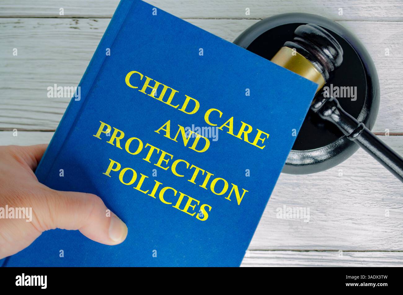 Hand holding Child Care and Protection Policies book with gavel ...
