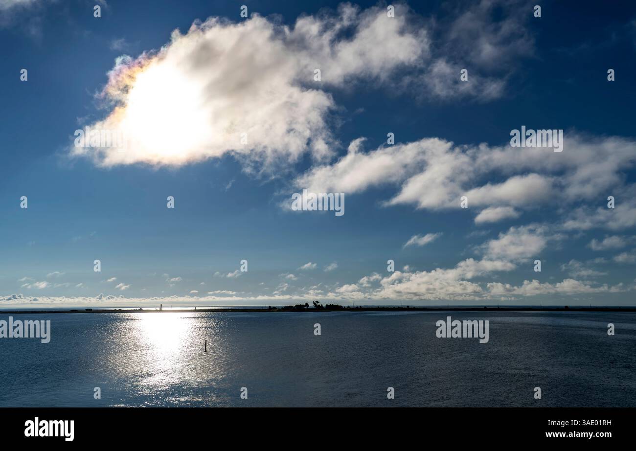 A serene landscape featuring a calm body of water reflecting sunlight ...