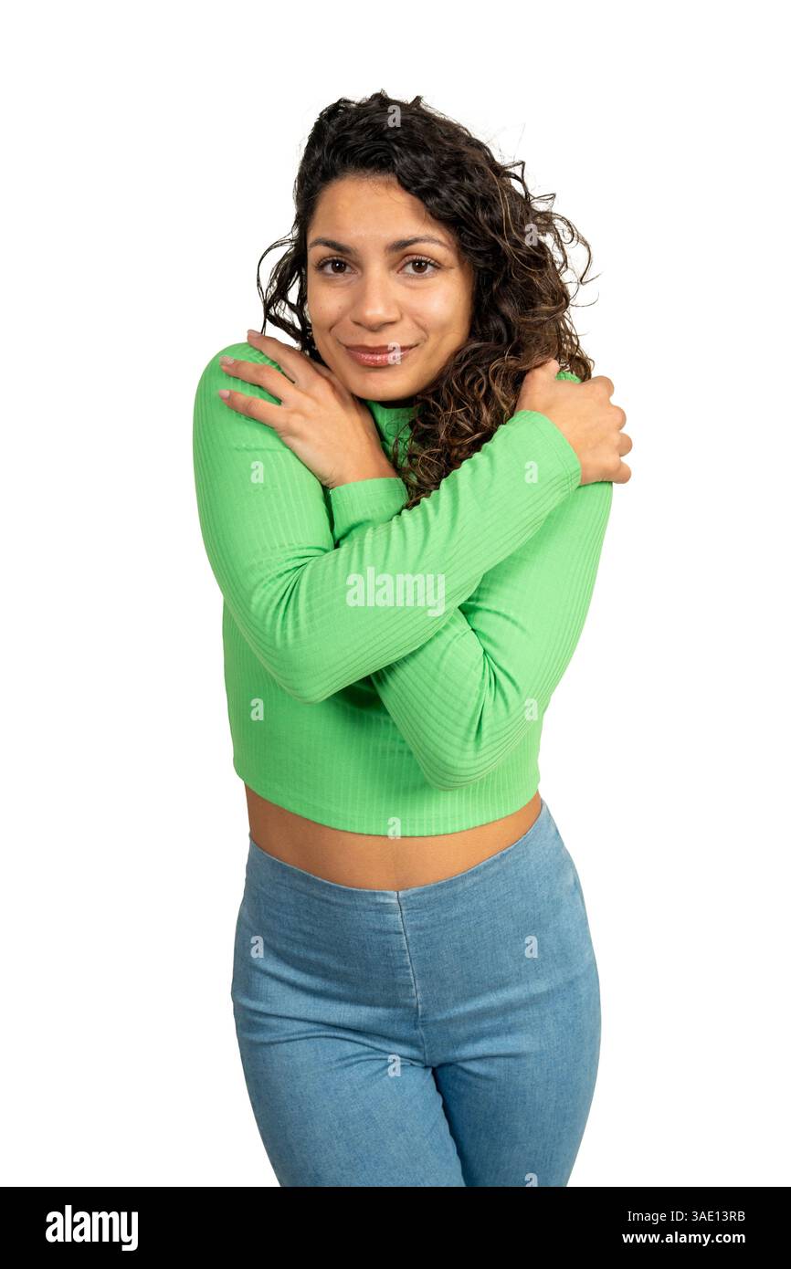 Studio portrait of a cheerful young latin woman hugging herself ...