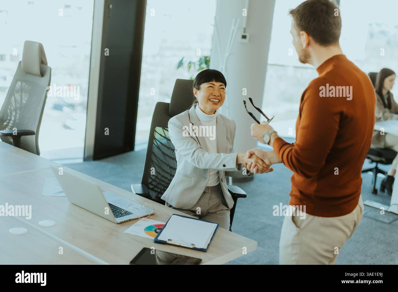 Bright office environment sees a joyful handshake between a male and ...